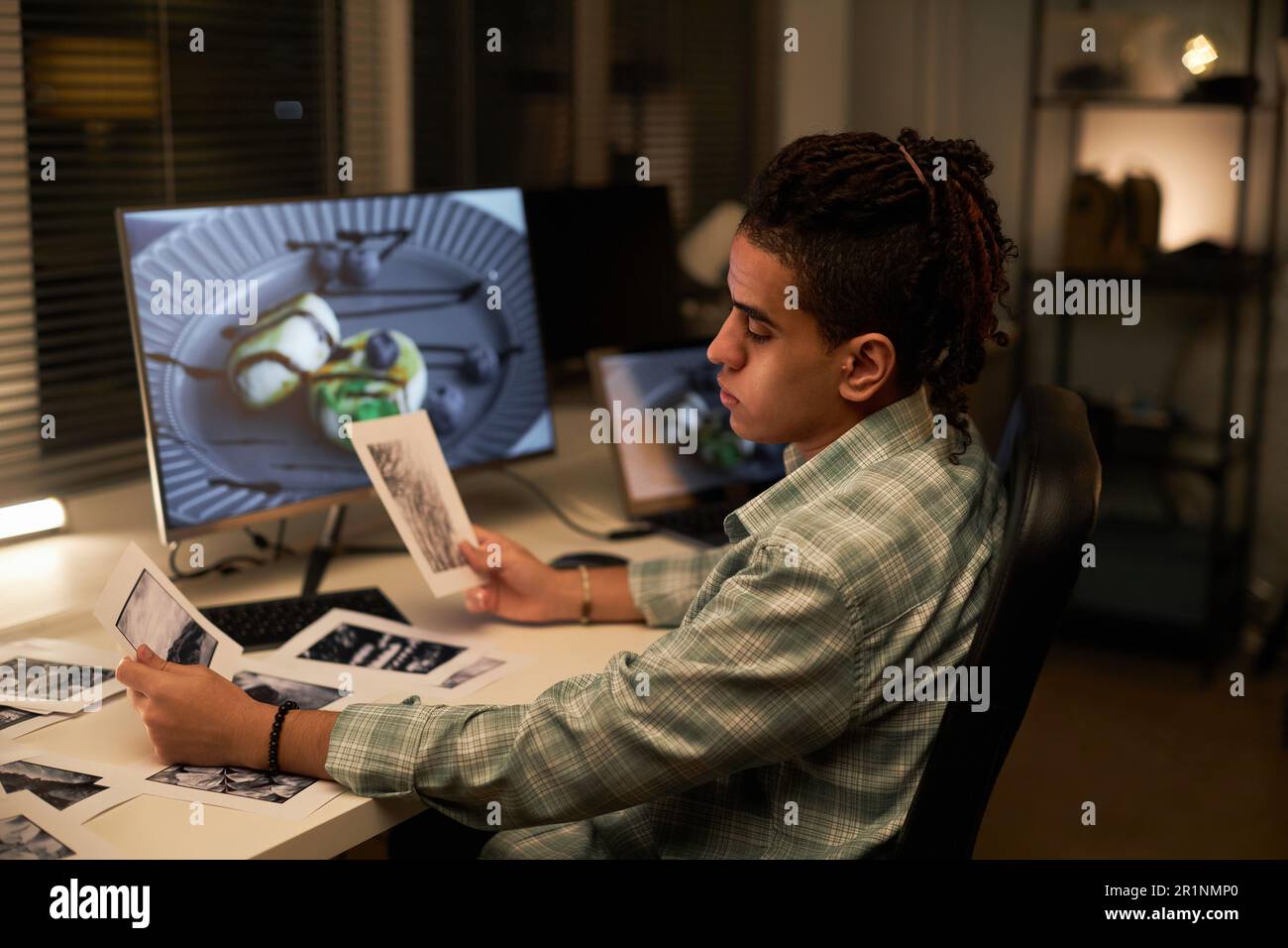 Young professional photographer examining old photos while sitting at ...