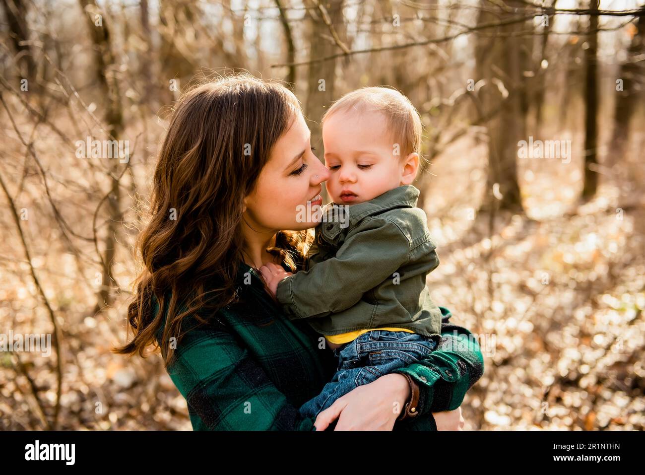 Smiling mother brings face close to baby cheek in woods in Fall Stock ...