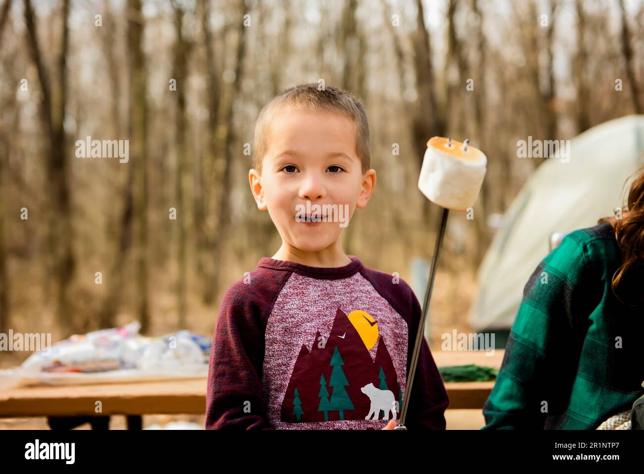 Excited boy holds up cooked marshmallow on stick at campsite in Fall ...