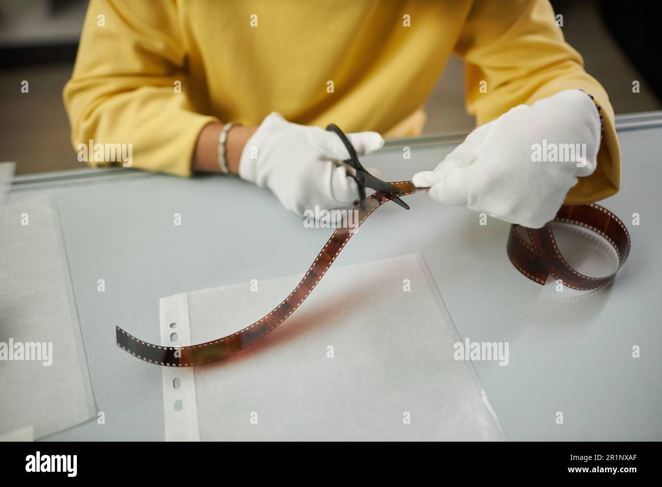 Close-up of photographer in white gloves cutting photo film with ...