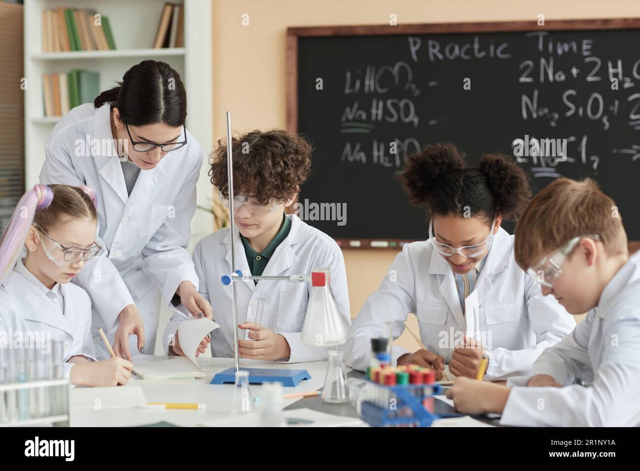 Diverse group of children wearing lab coats in science class at school ...