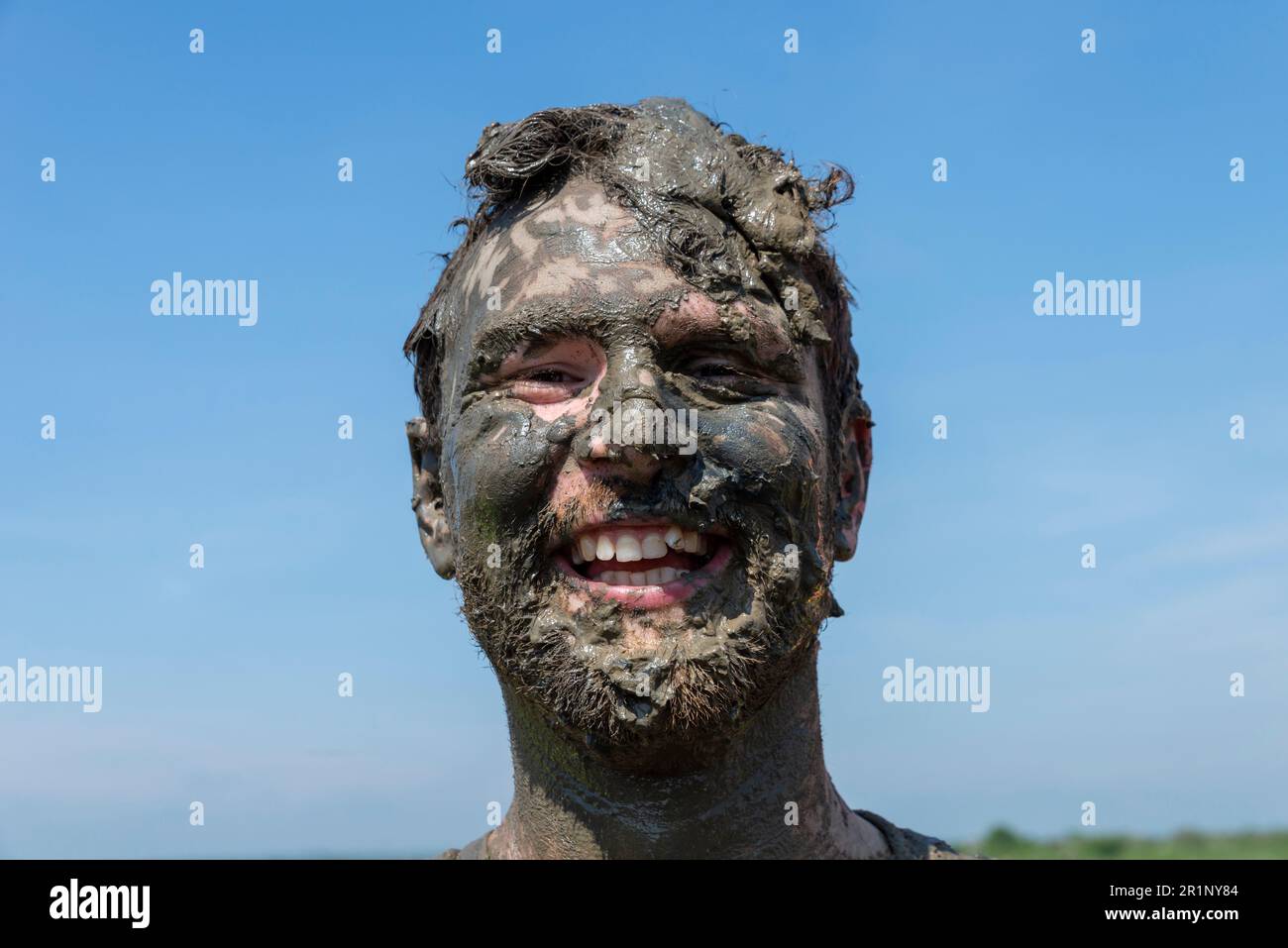 Male with muddy face after taking part in the Maldon Mud Race in Maldon, Essex, UK, in the mud ...