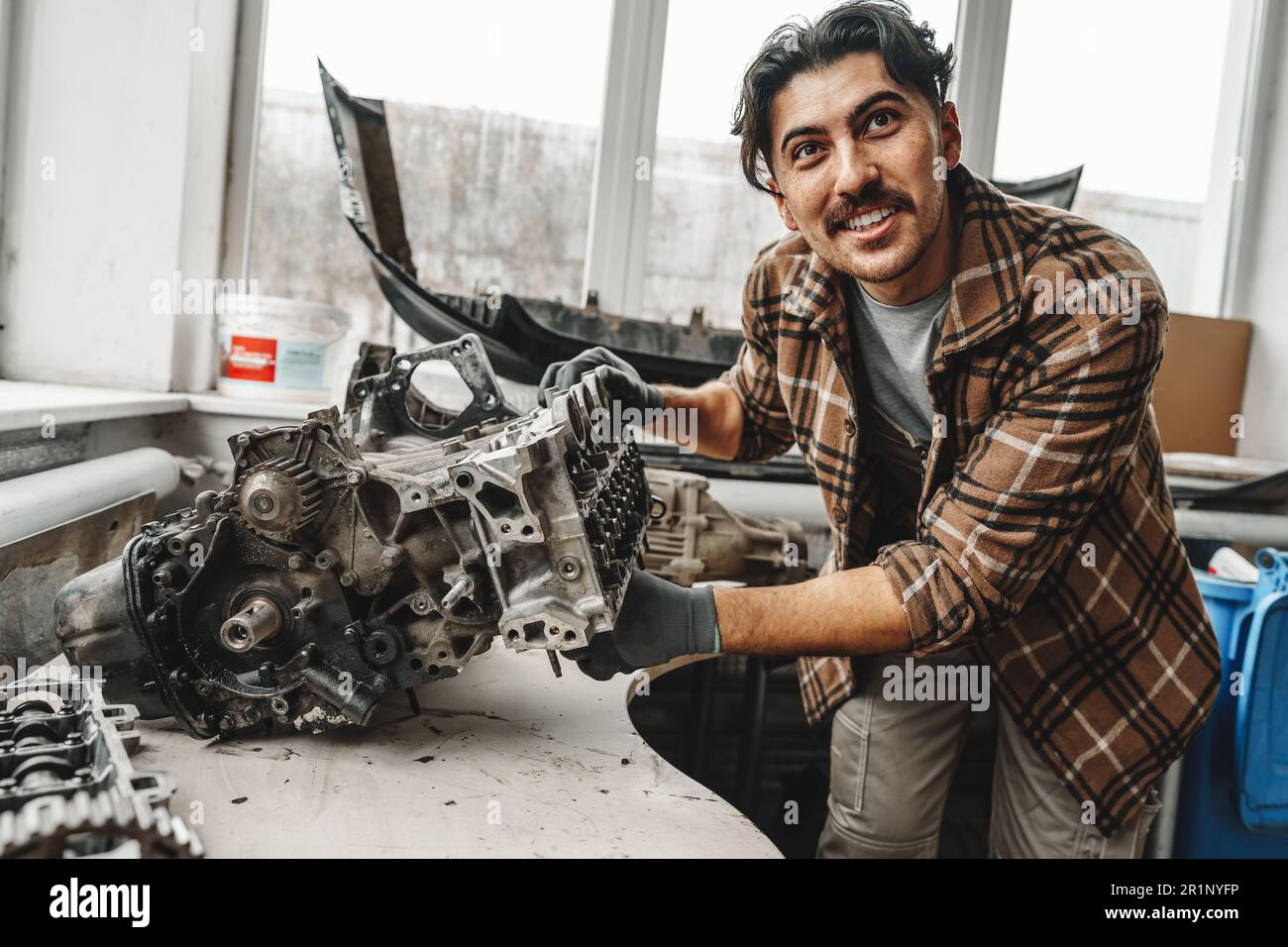 Workman disassembling car engine at the working table of the car ...