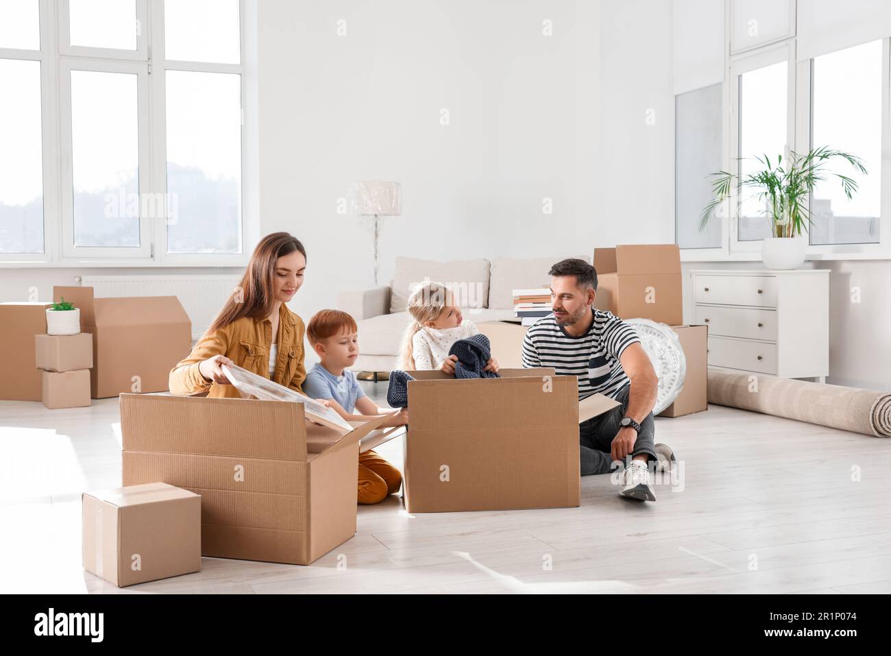 Family unpacking boxes in new apartment. Moving day Stock Photo - Alamy