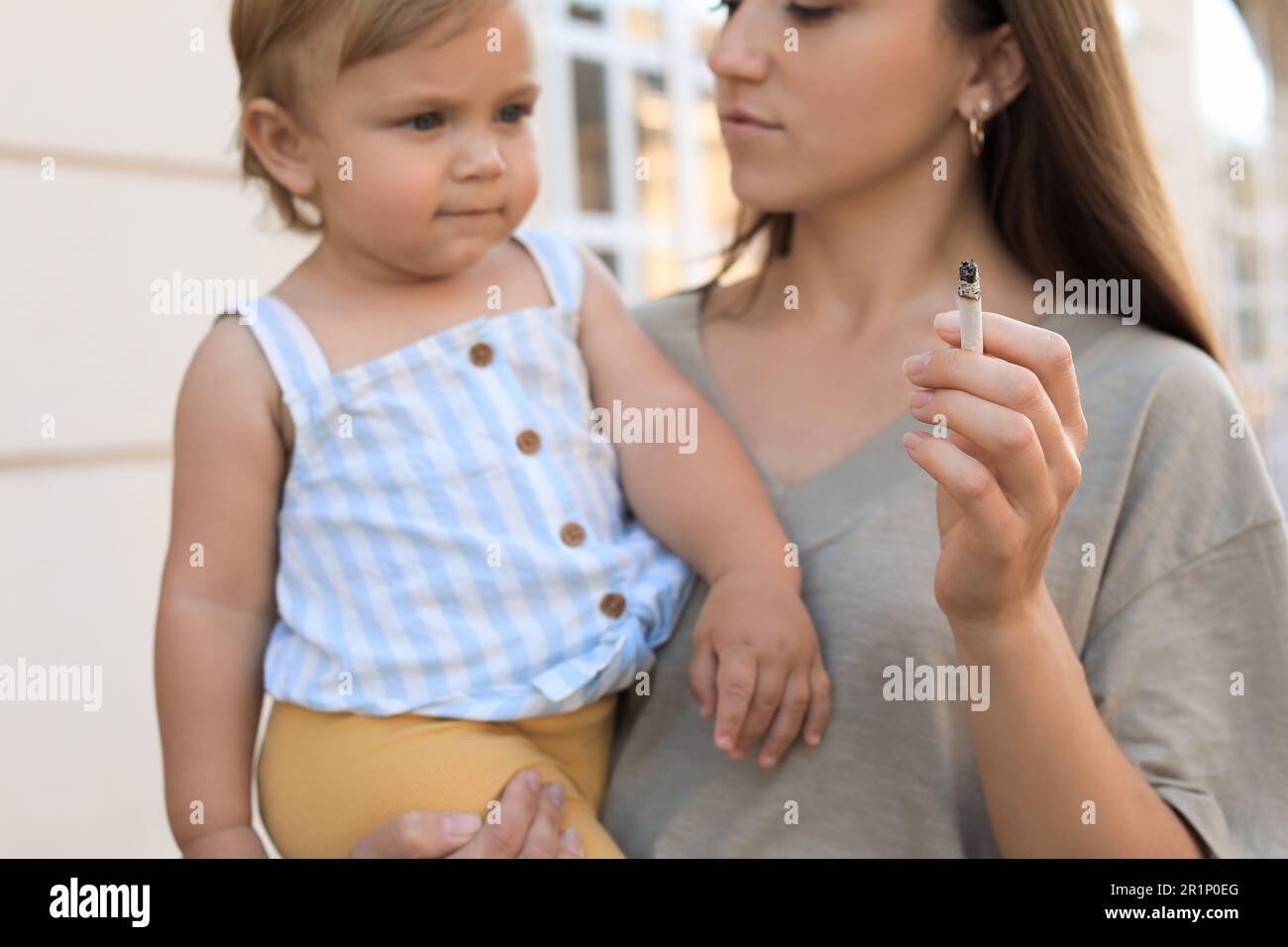 Mother with cigarette and child outdoors, focus on hand. Don't smoke ...