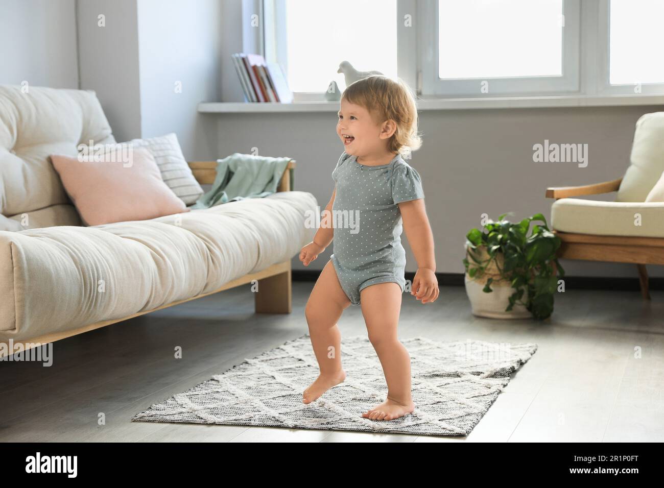 Cute baby learning to walk in living room Stock Photo - Alamy