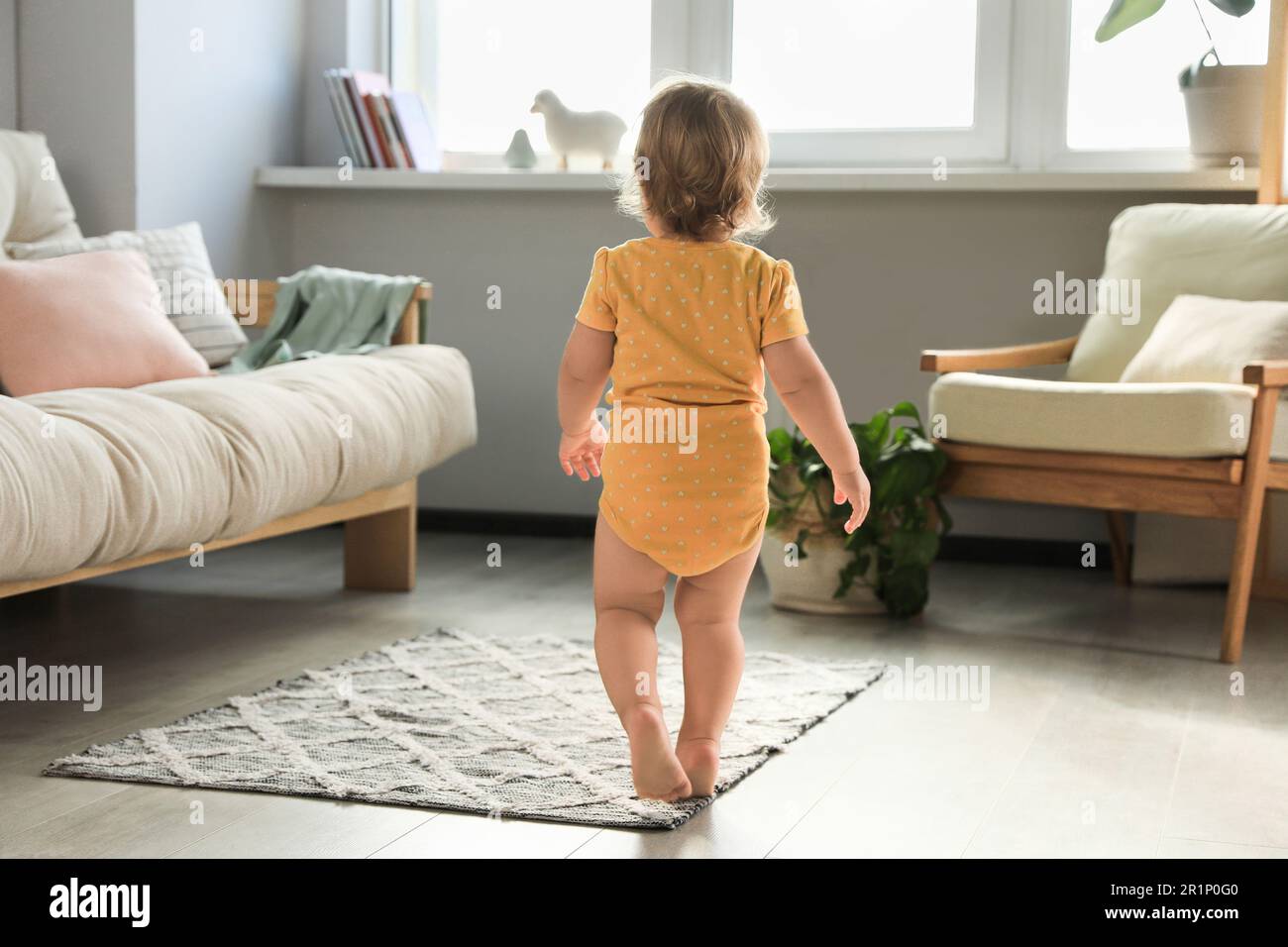 Cute baby learning to walk in living room Stock Photo - Alamy