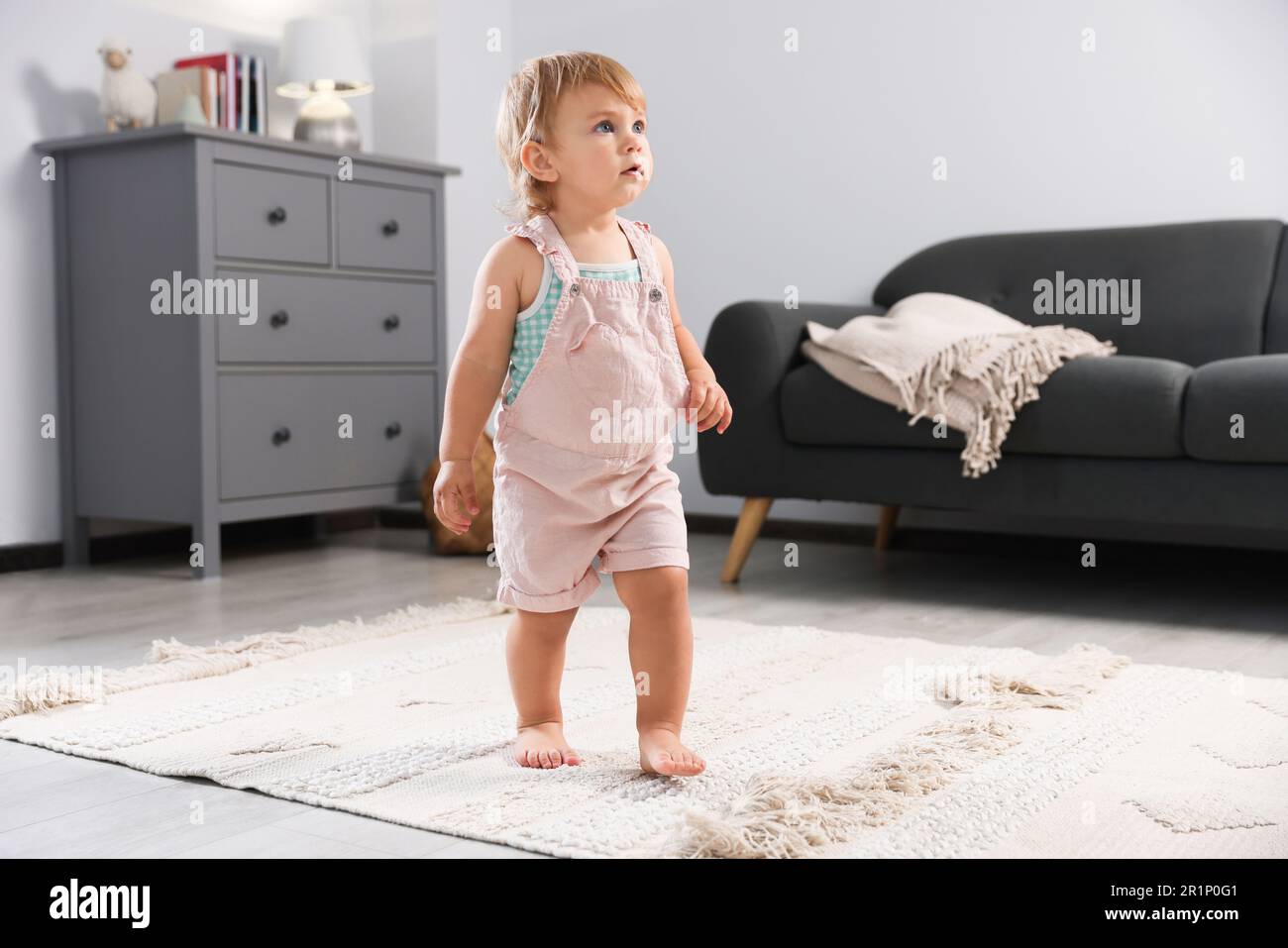 Cute baby learning to walk in living room Stock Photo - Alamy