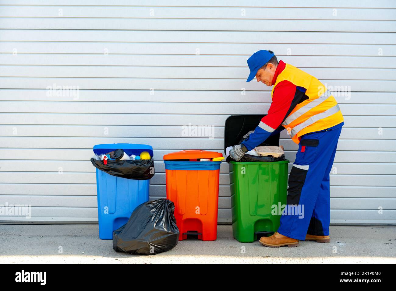 Janitor takes garbage out of trash container outdoors Stock Photo - Alamy