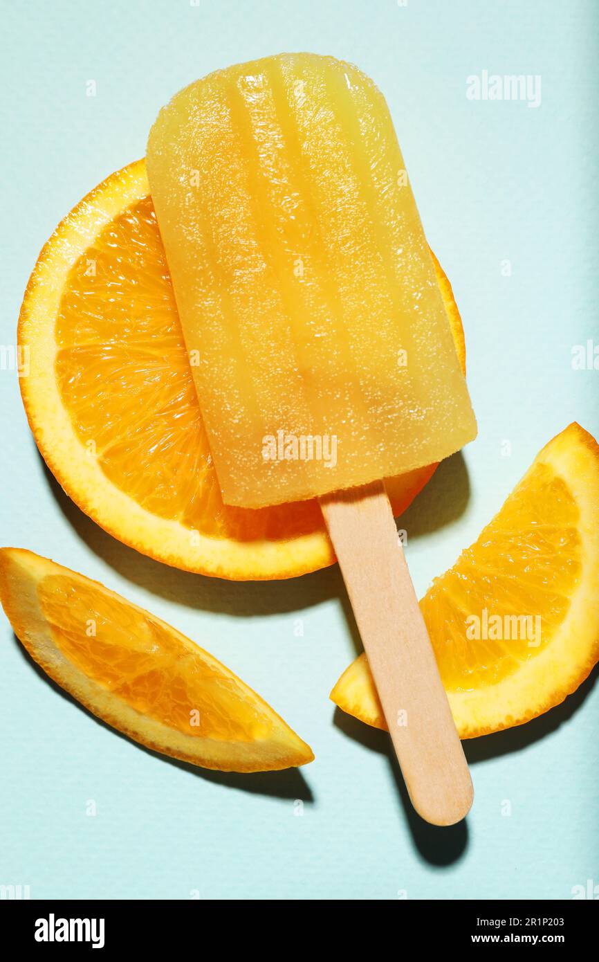 Tasty orange ice pop on pale light blue background, top view. Fruit ...