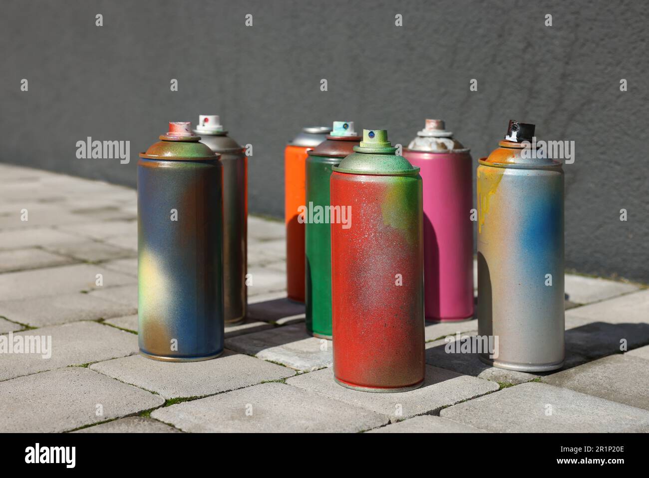 Cans of different spray paints on pavement near wall Stock Photo - Alamy