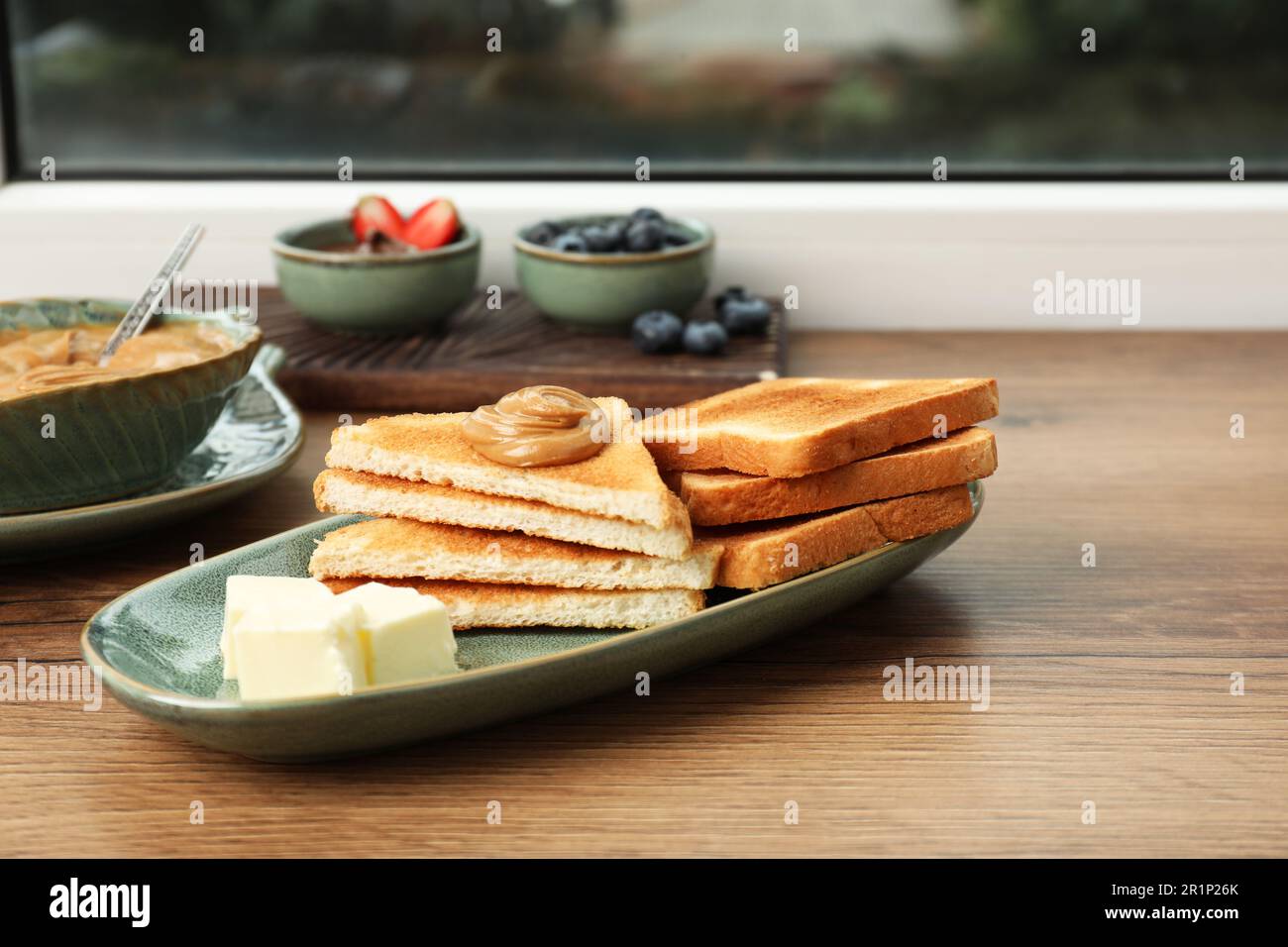 Tasty toasts and different toppings on wooden table at window Stock ...
