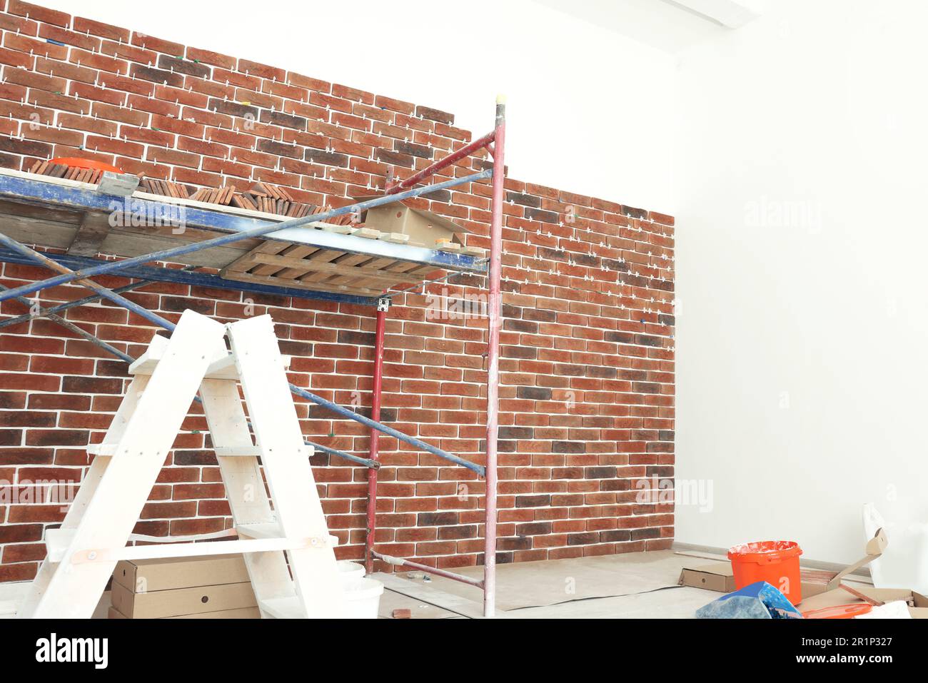 Scaffolding near wall with decorative bricks and tile leveling system ...