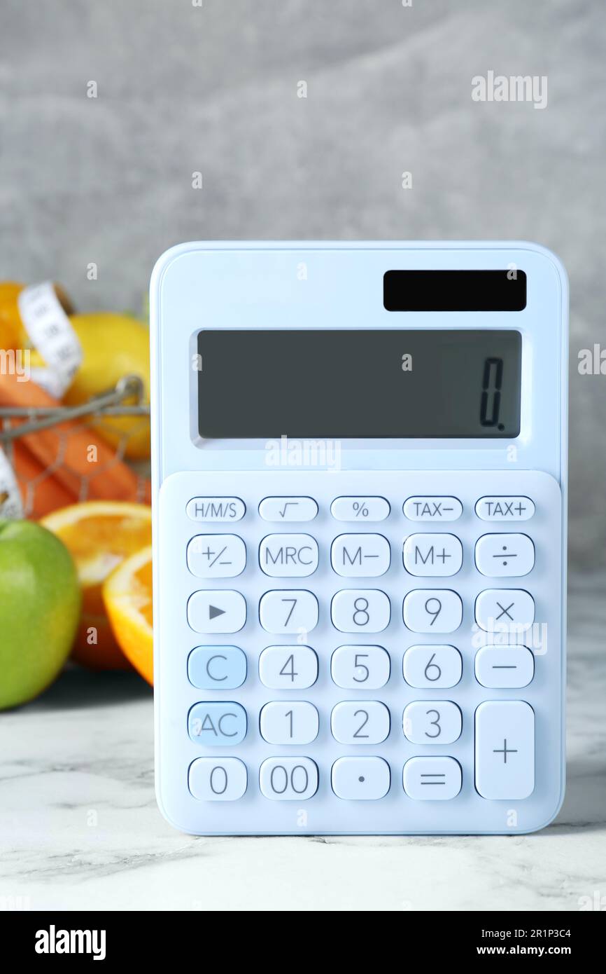 Calculator and food products on white marble table. Weight loss concept ...