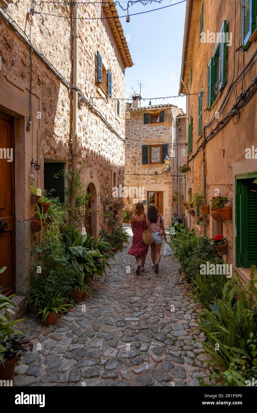 Tourists walk through alley, mountain village Valldemossa with typical ...