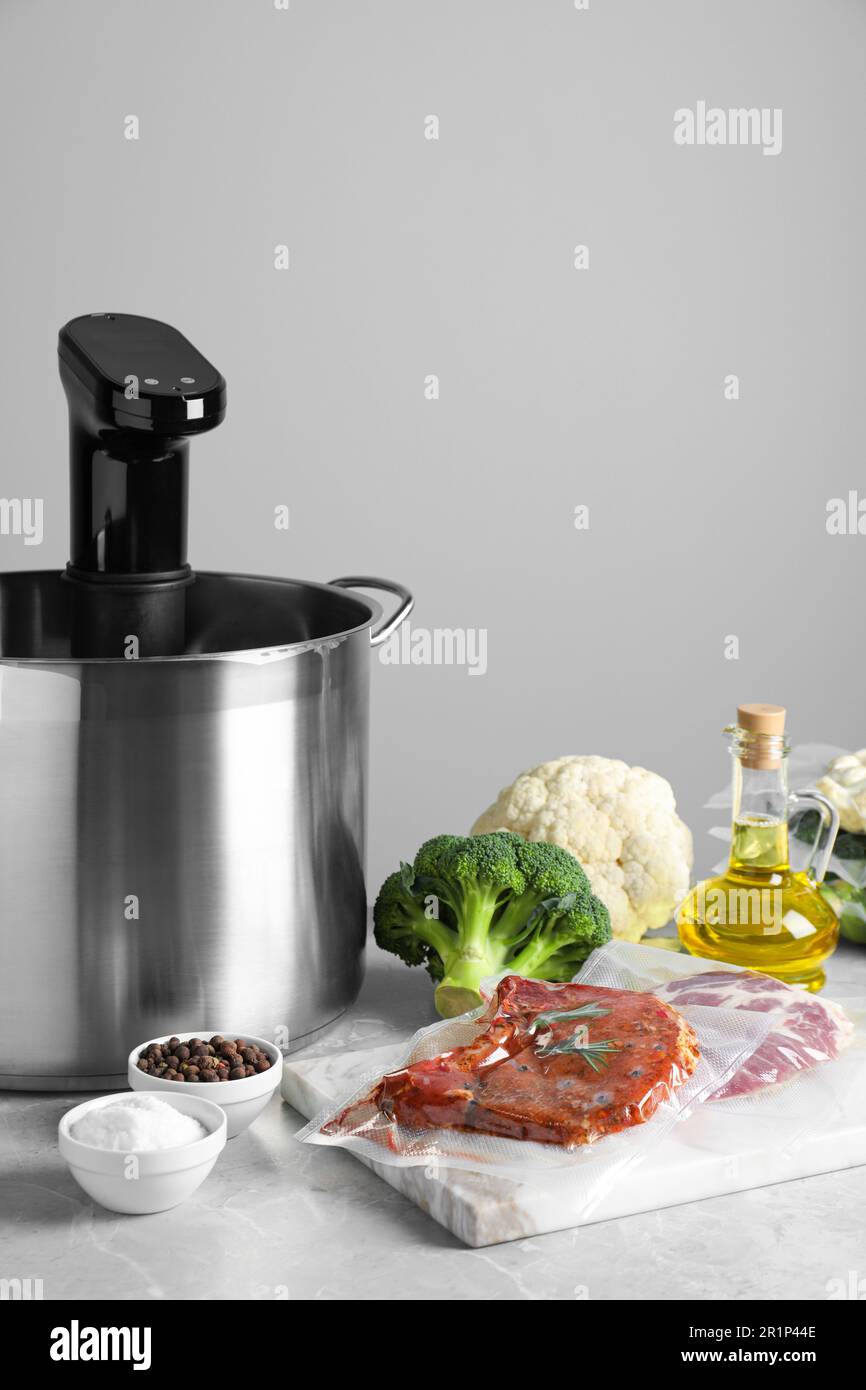 Thermal immersion circulator in pot and ingredients on light grey table ...