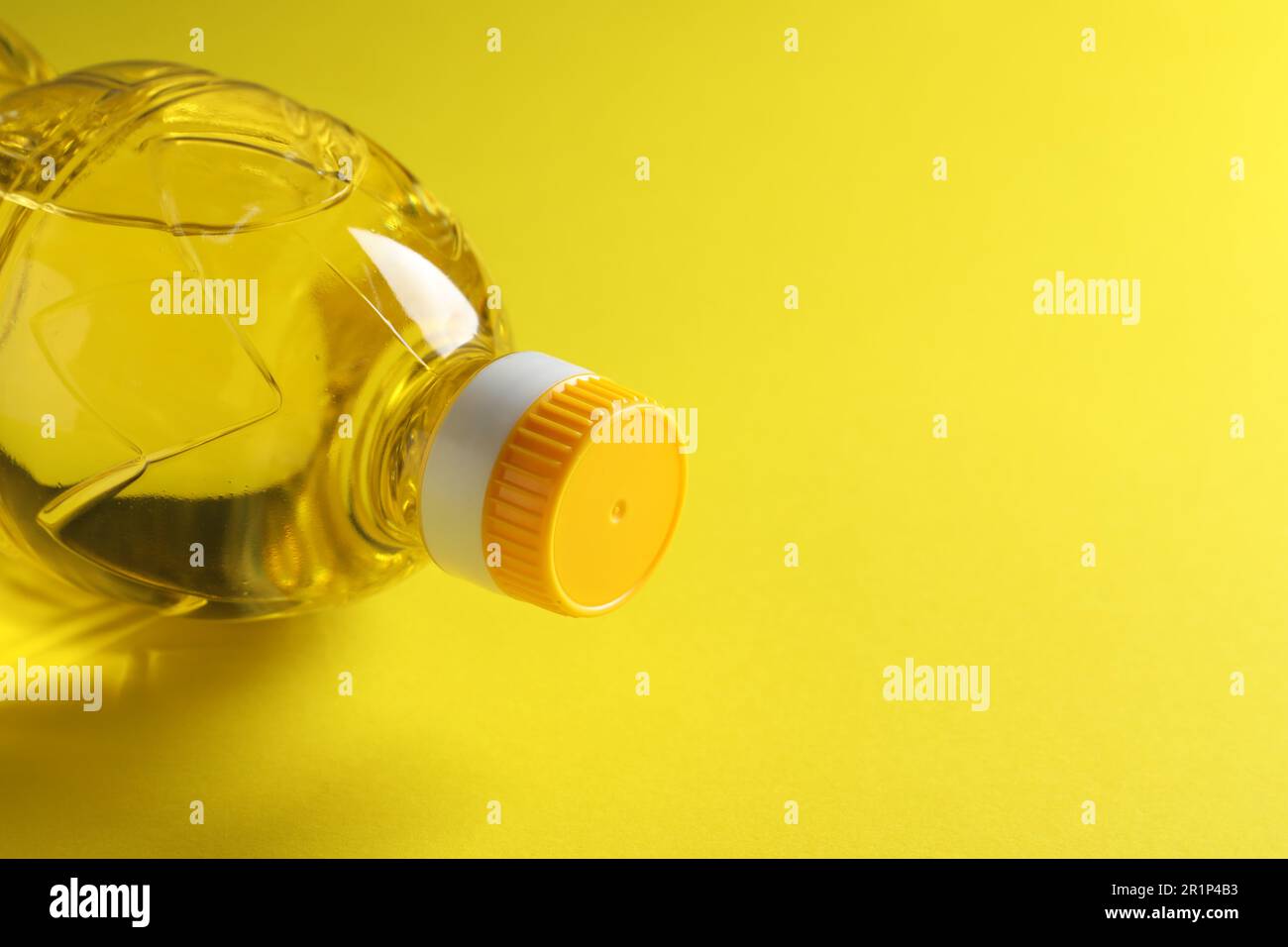 Plastic bottle of cooking oil on yellow background. Space for text ...