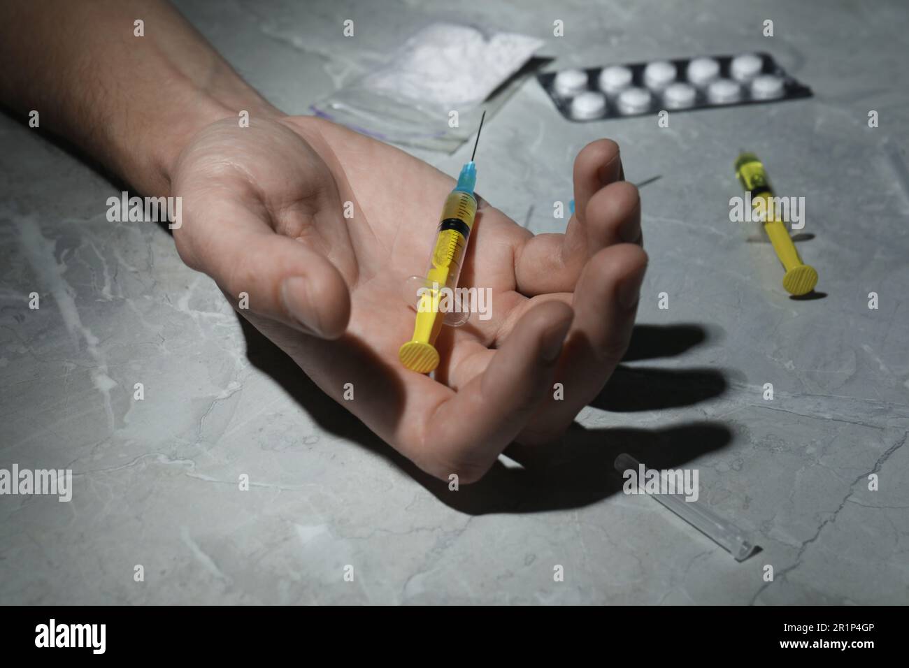 Man with syringe on grey marble table, closeup. Drug addiction Stock ...