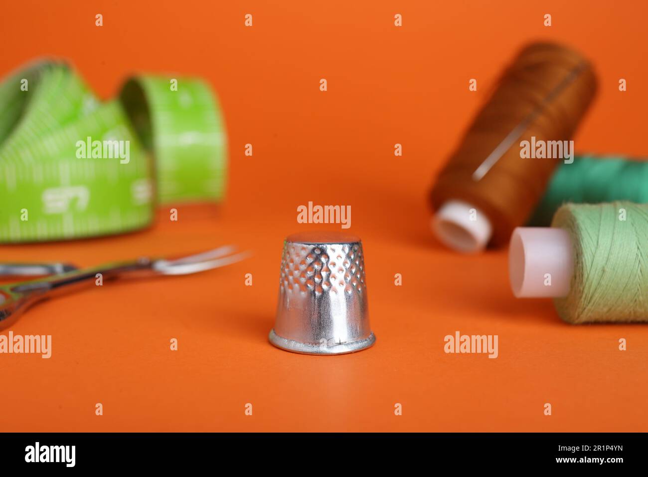 Thimble and different sewing tools on orange background Stock Photo - Alamy