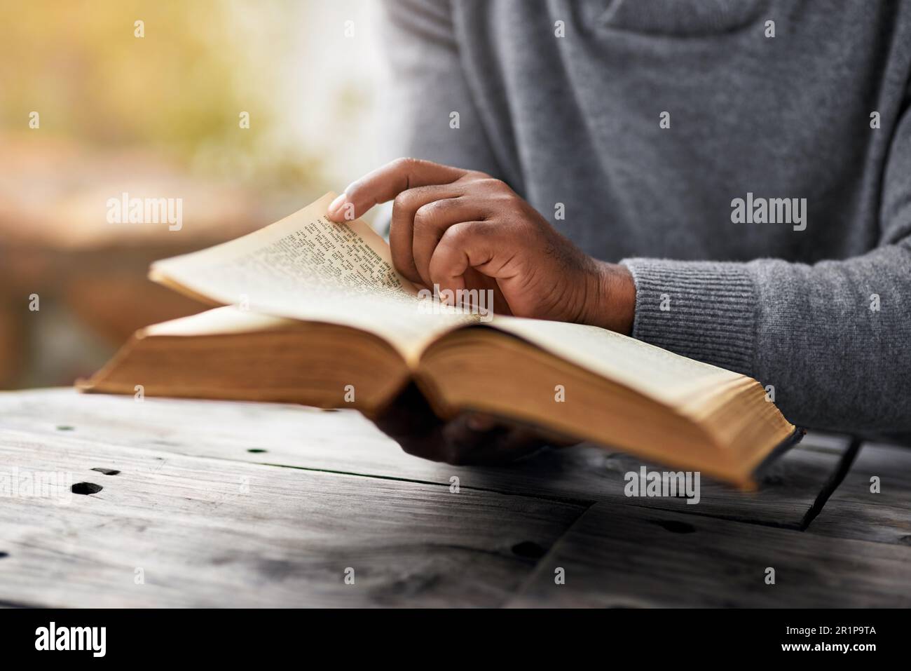 Hands, story and a man reading the bible at a table outdoor in the park ...