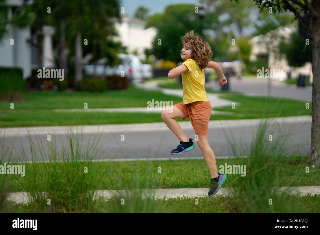 Cute kid boy running across american neighborhood street. Summer ...