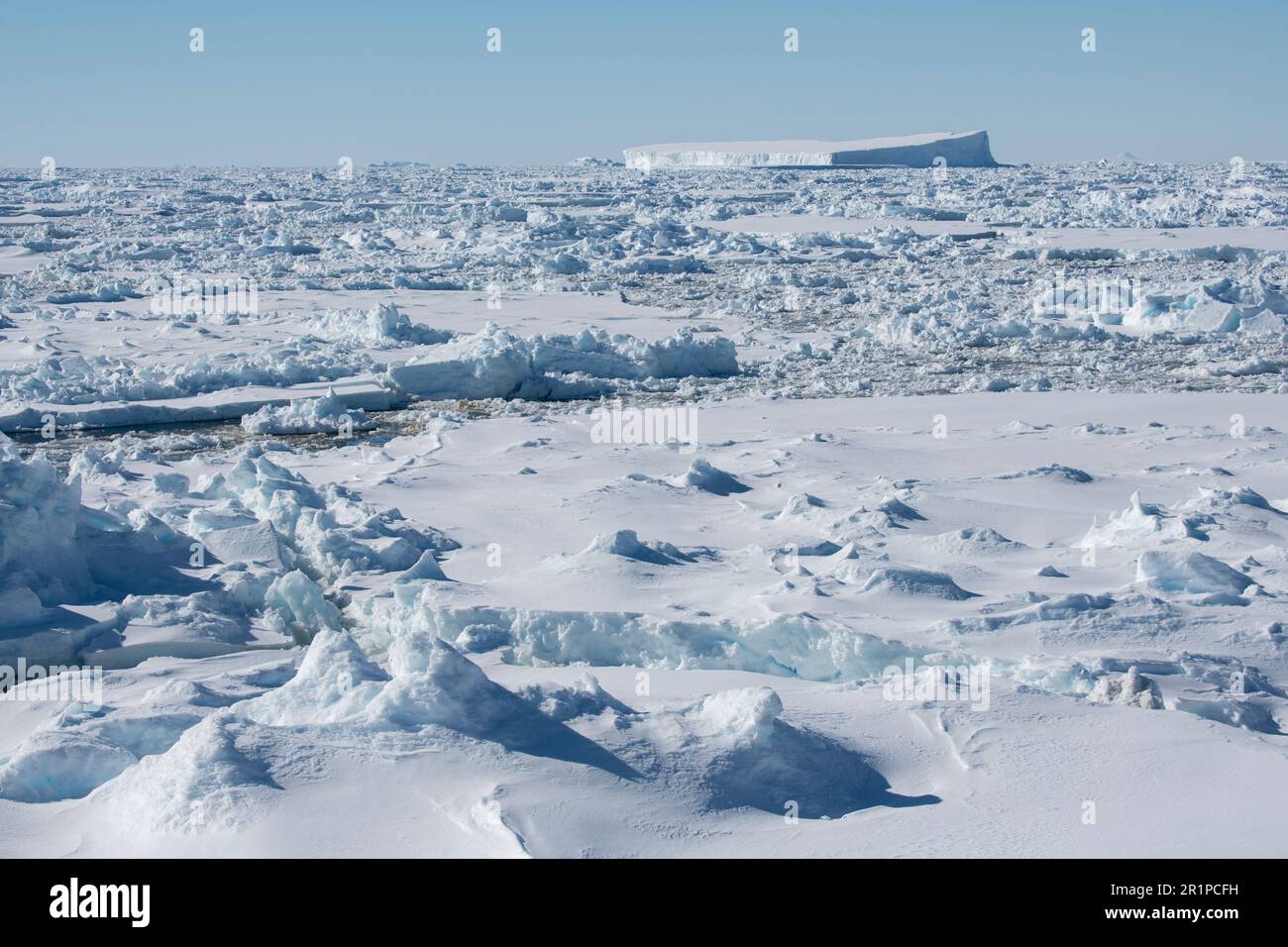 Antarctica, pack ice on the Amundsen Sea with iceberg in the distance ...