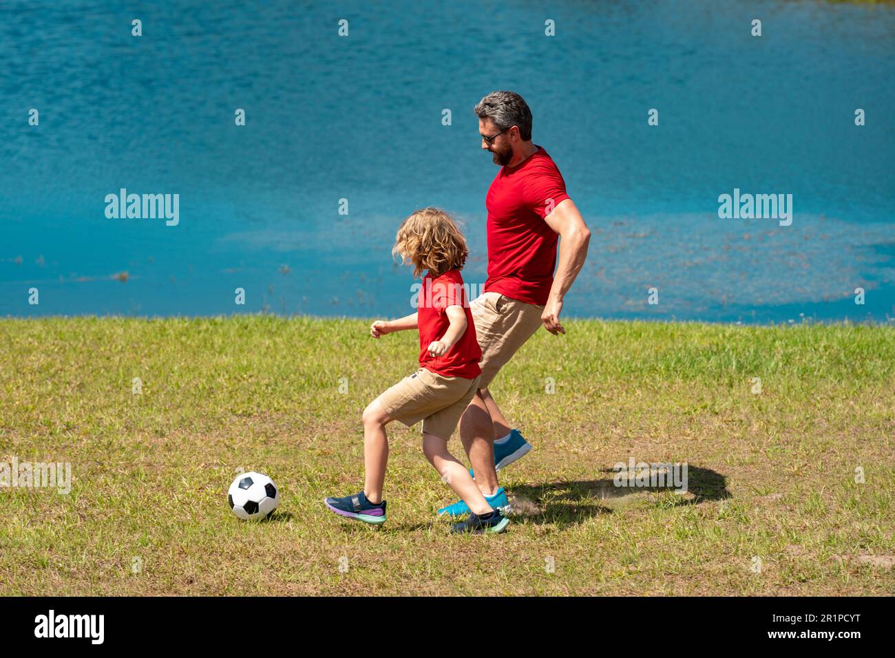 Dad and son playing football together on green meadow. Father and son ...