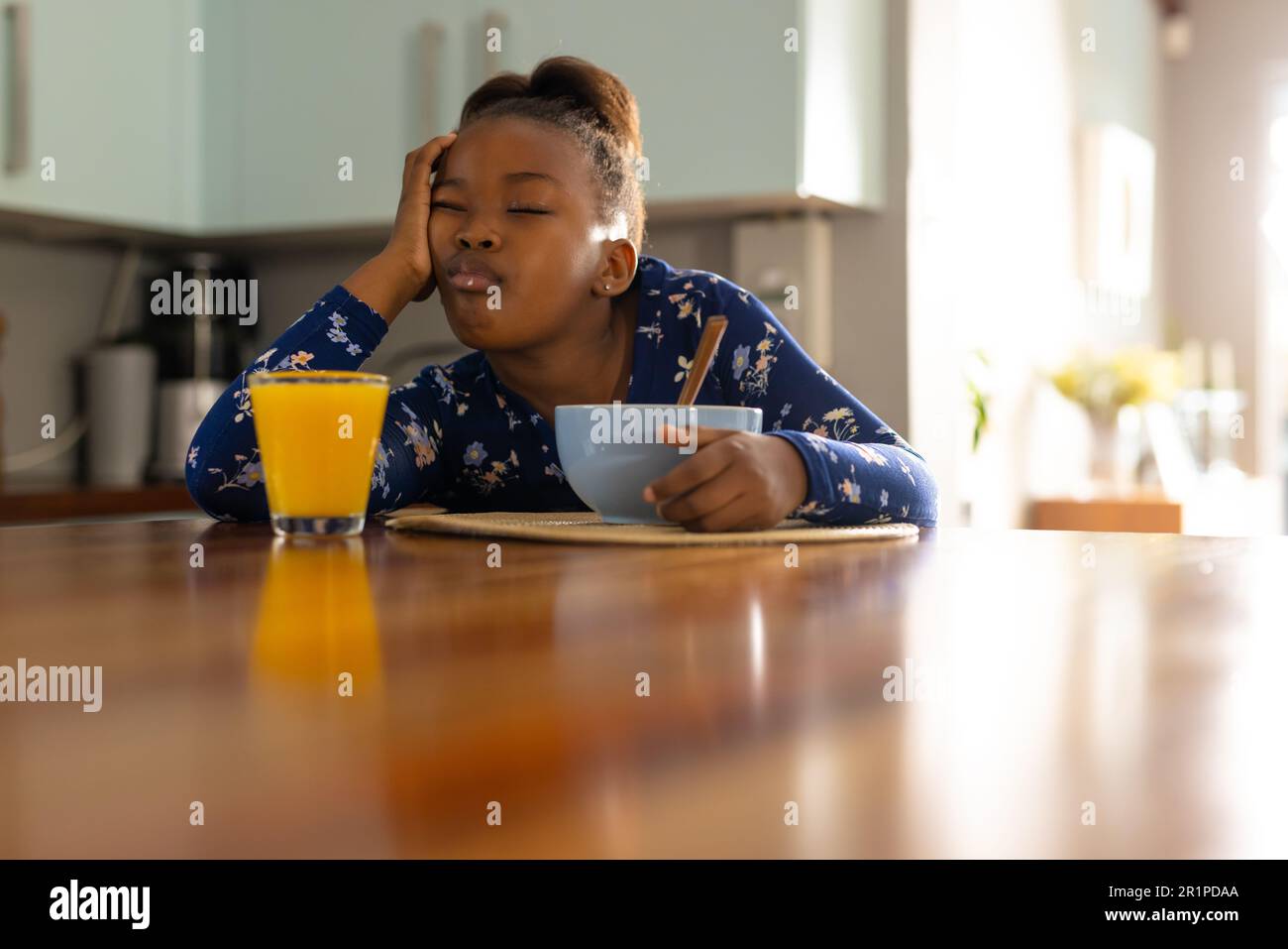 Tired african american girl sitting half asleep with breakfast cereal ...