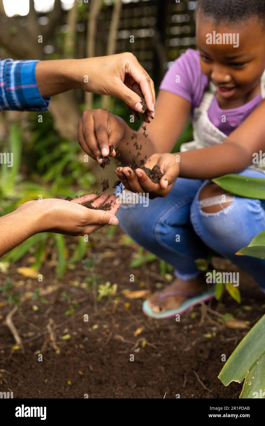 Hands of african american mother and happy daughter preparing soil for ...