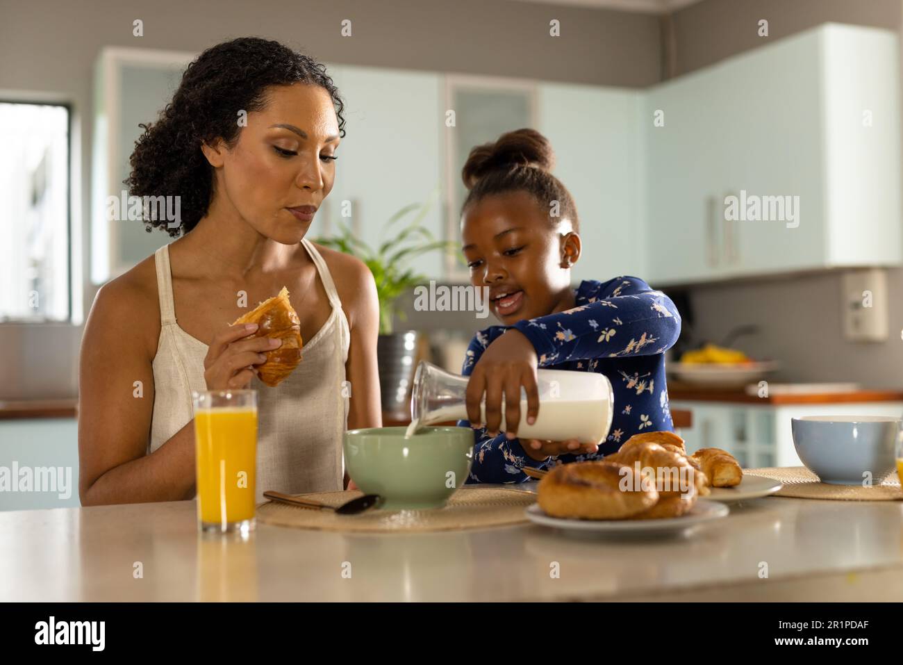 Happy african american mother and daughter sitting at kitchen island ...