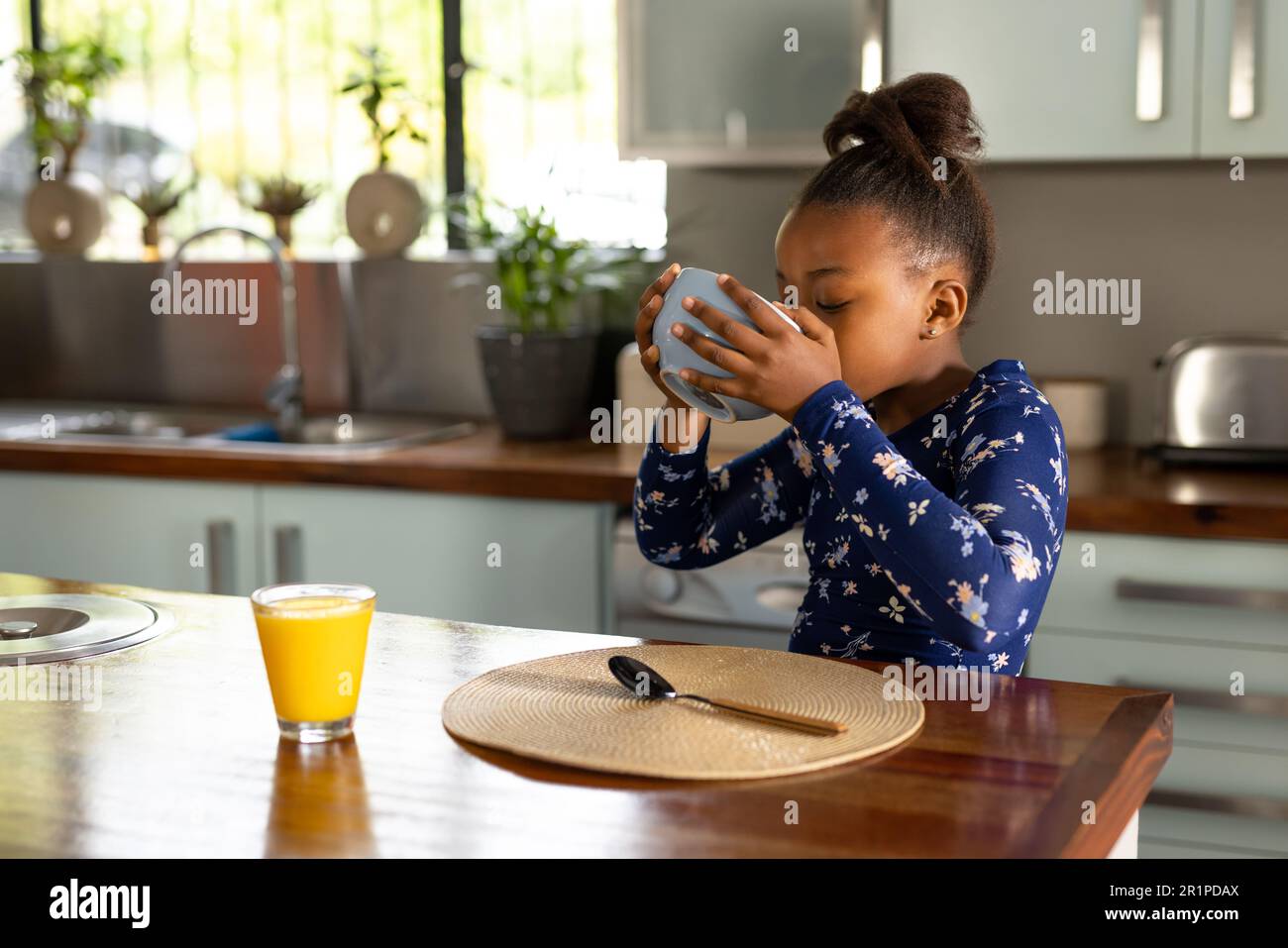 Happy african american girl finishing her breakfast cereal sitting in kitchen Stock Photo - Alamy