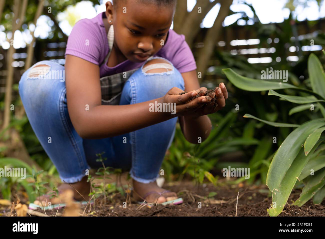 Happy african american girl preparing soil for planting in garden Stock ...