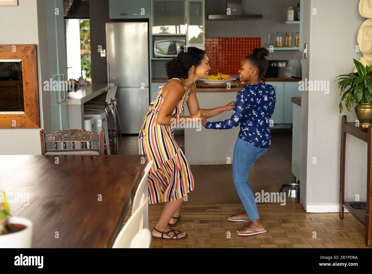 Happy african american mother and daughter having fun dancing together ...
