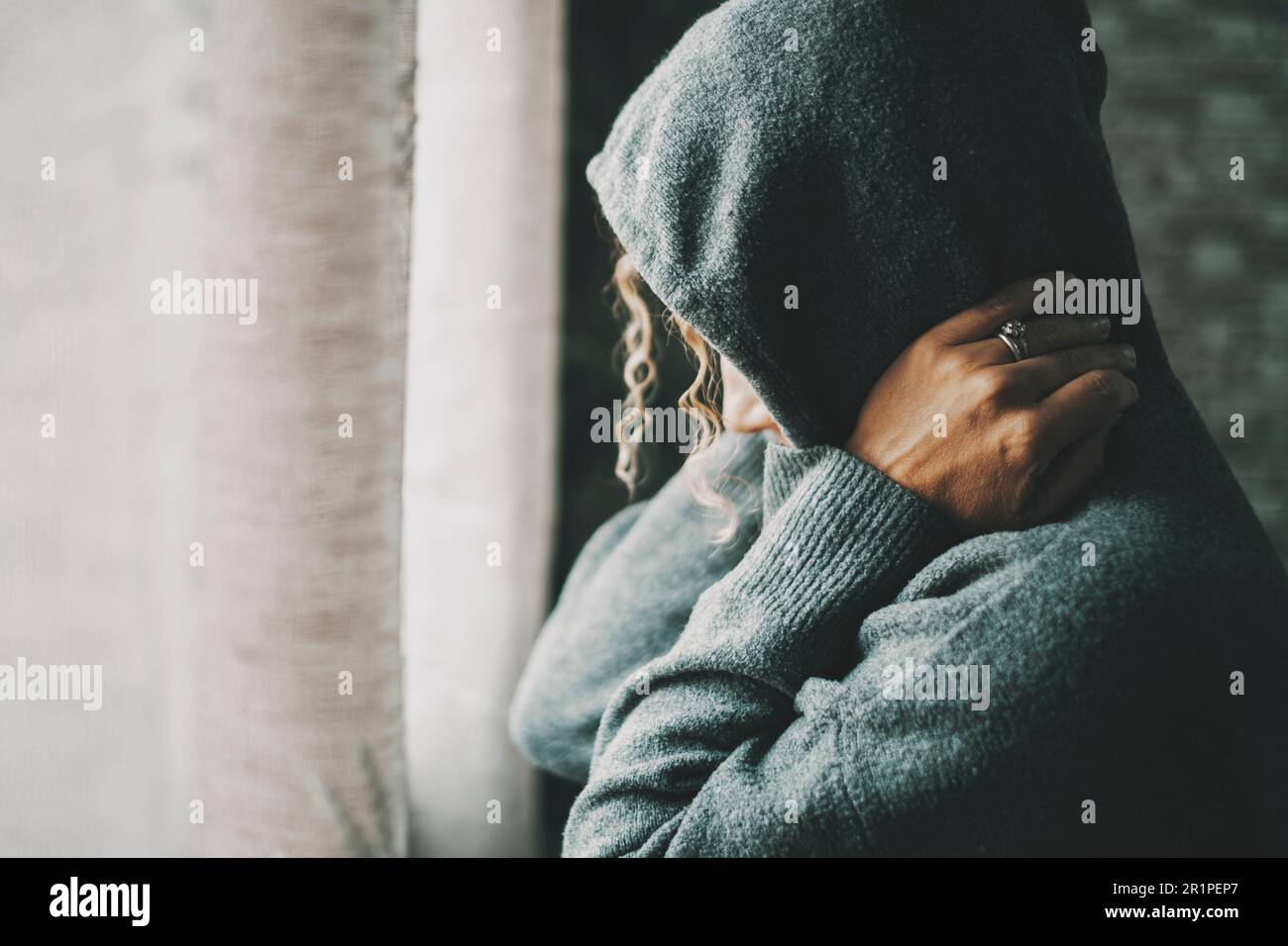 Desperate woman at home indoor wearing sweater with hood on and ...