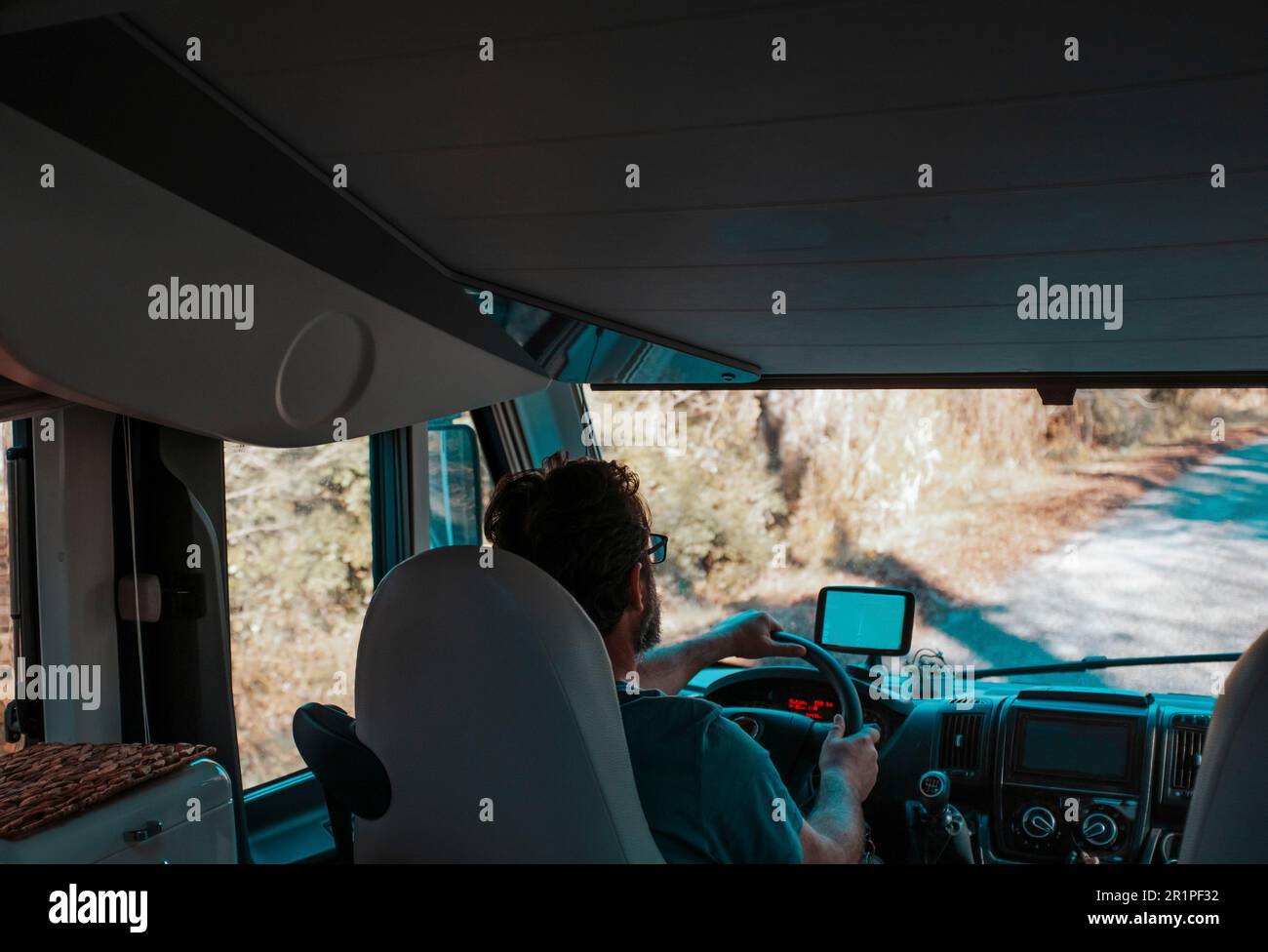 One man driving big camper van on the road viewed from interior ...