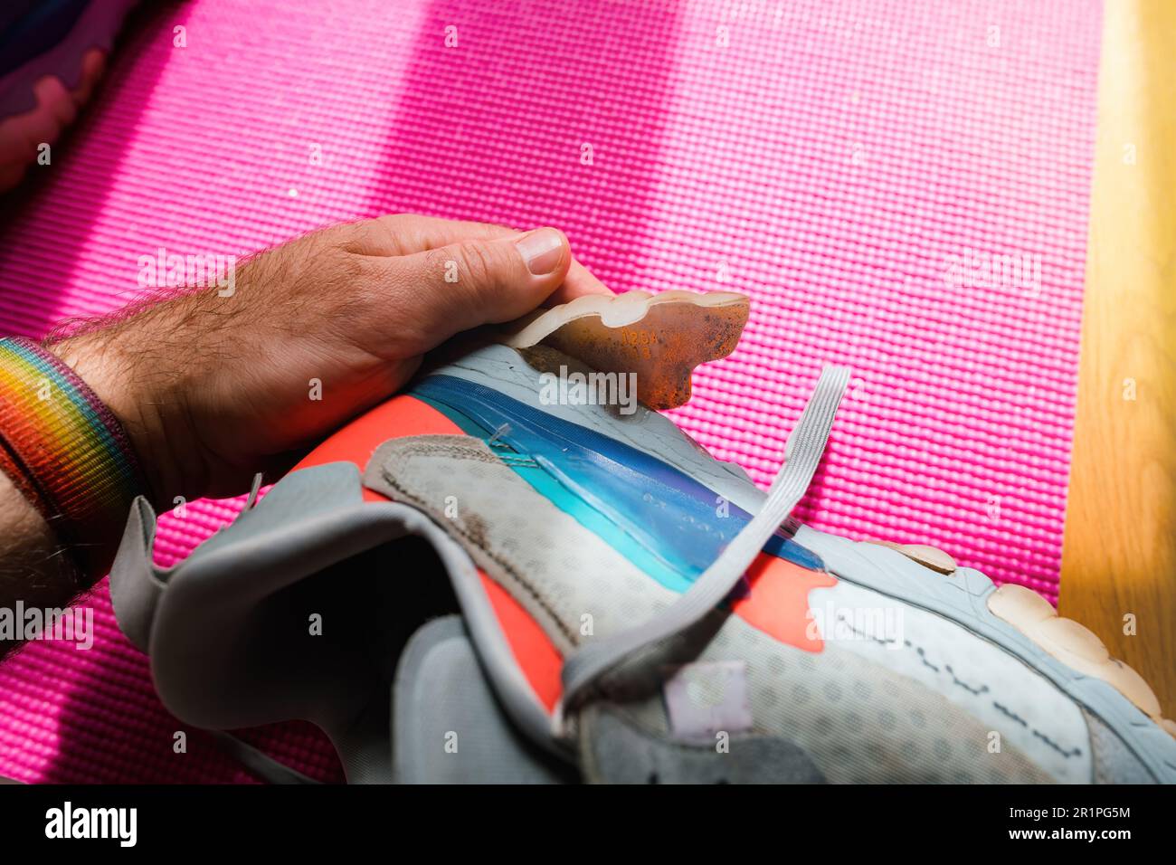 A man inspects a worn running shoe with his fingers, revealing the ...