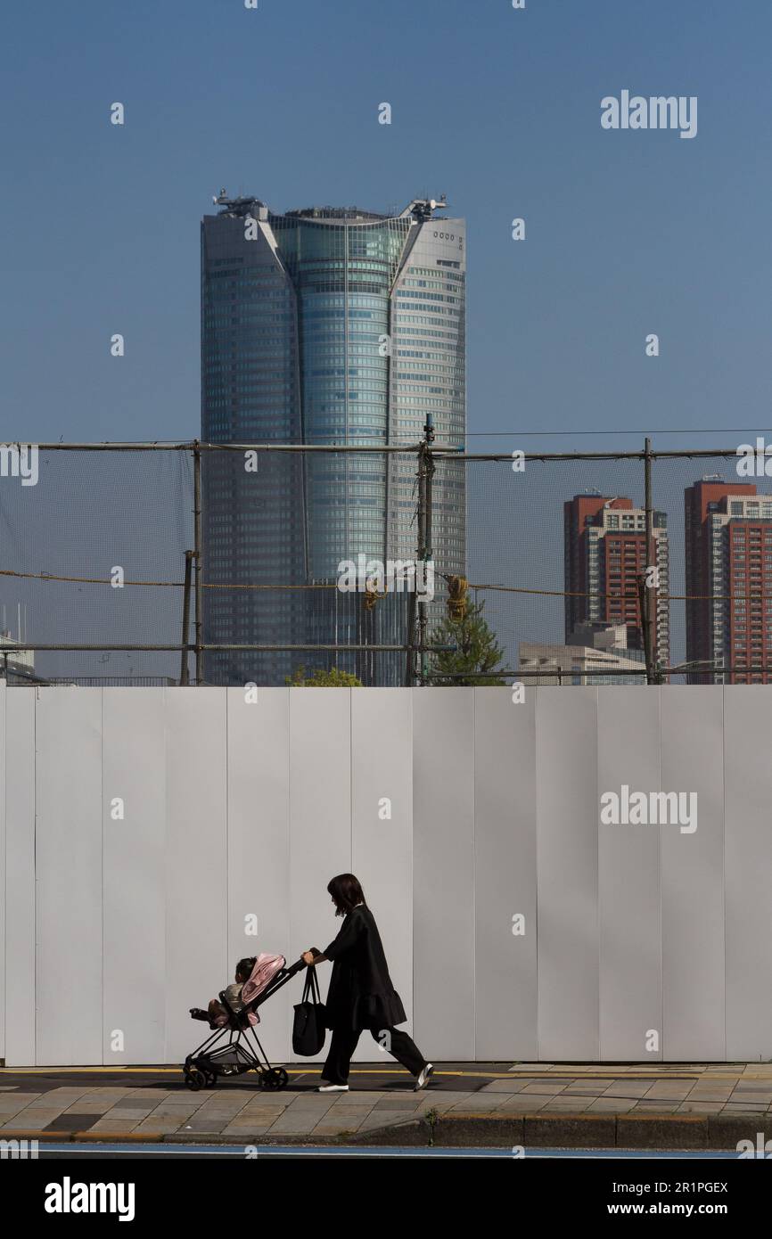 A woman pushes a pushchair with a child in front of a construction site ...