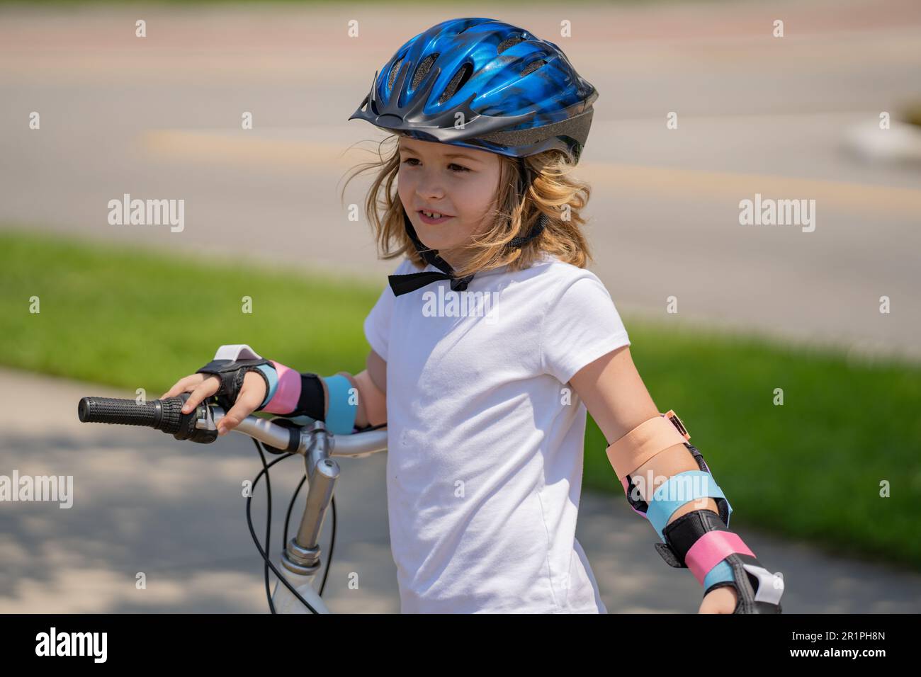 Kid riding bike on a summer park. Child in safety helmet riding bike ...