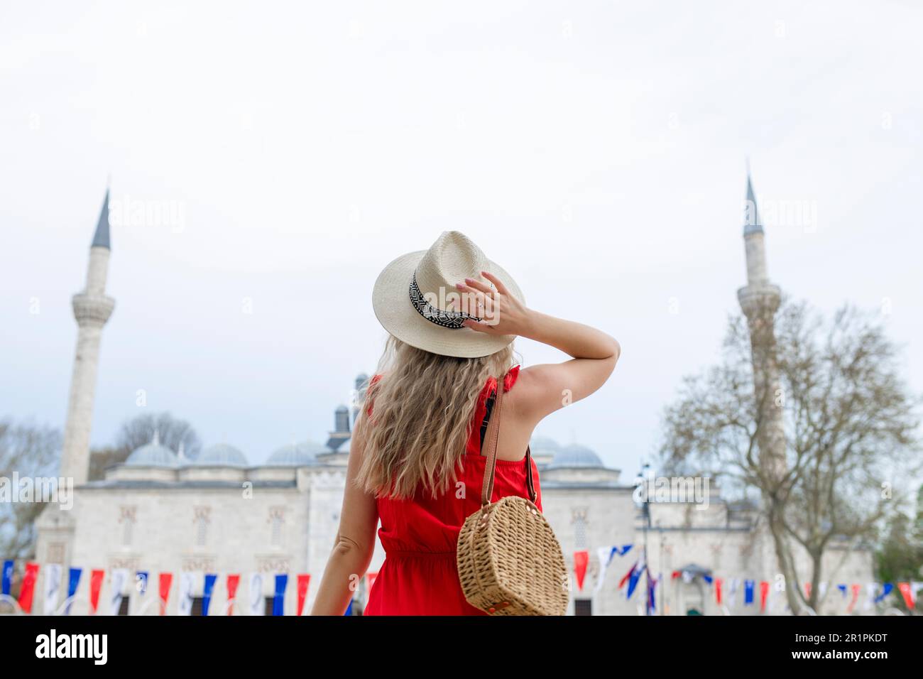 A beautiful travel blogger girl in a long red dress and a straw hat is ...