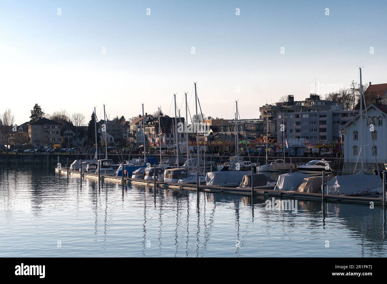 An idyllic scene of sailboats in Bodensee Lake harbor with the city in ...