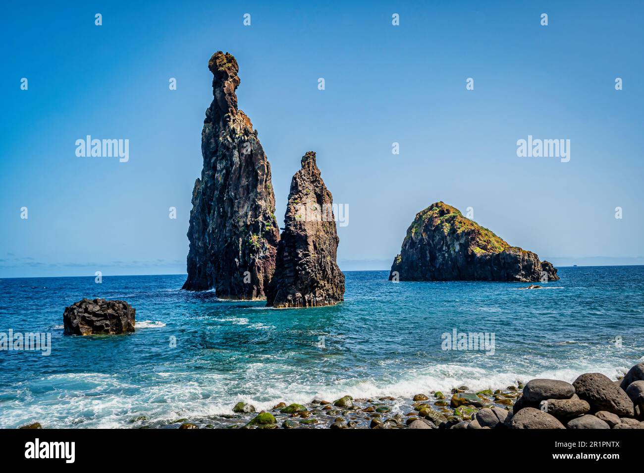 Two large rock formations protrude from the clear blue ocean in the ...