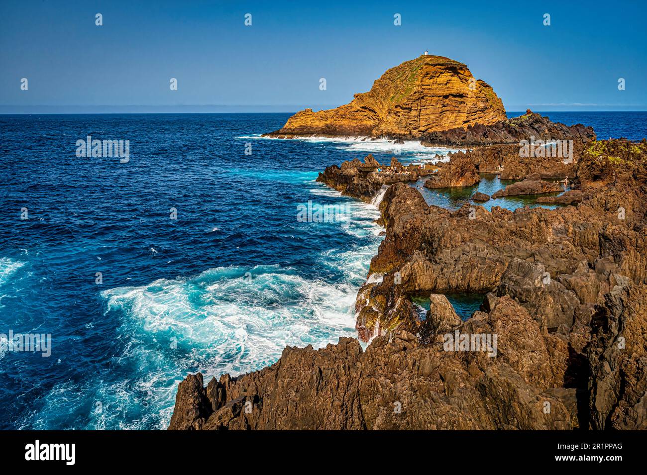 A picturesque landscape featuring a rocky shoreline at the edge of a ...