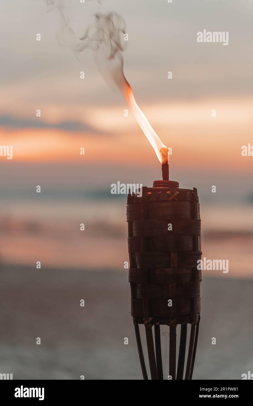 A vertical shot of a Tikki Torch with the sun setting in the background ...