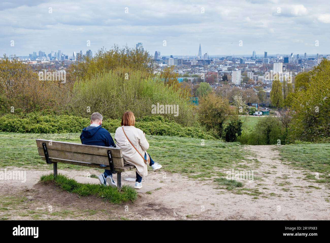 Two people sitting on a bench take in the view across the city from ...