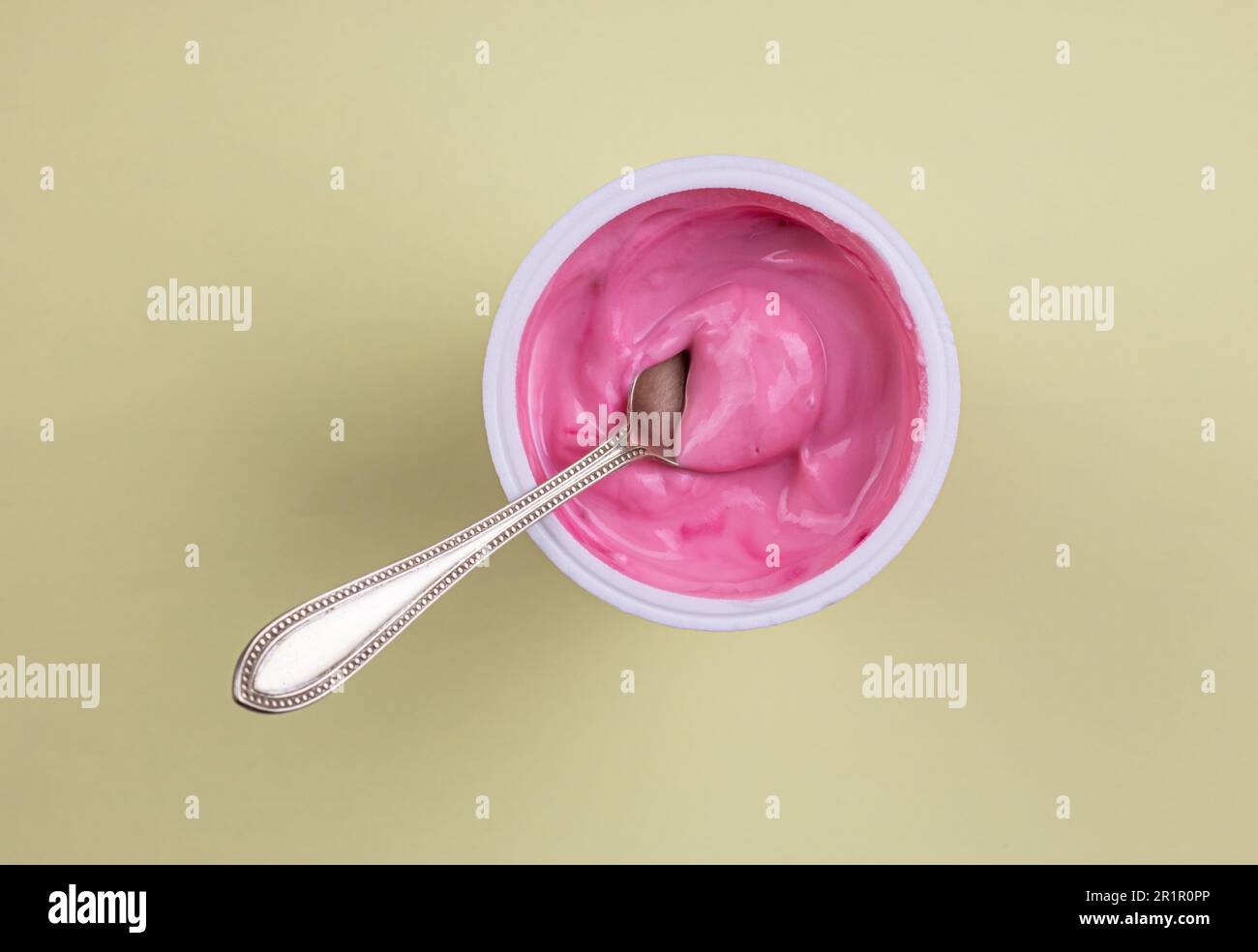 Pink red velvet flavour yogurt in plastic cup isolated on yellow pastel ...