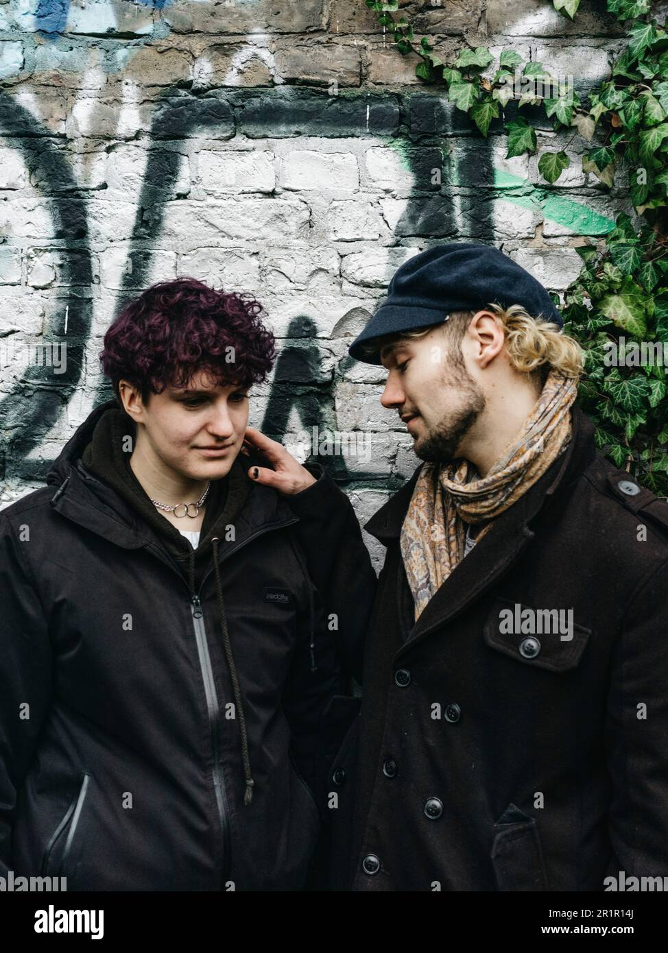 Non binary couple in front of wall with graffiti hi-res stock ...