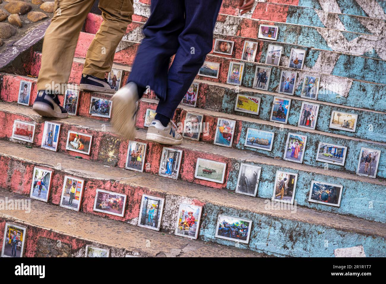 Two people climb a colorfully painted staircase with street art in ...