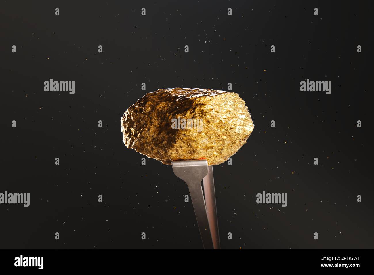 A close up on a pure shiny gold piece held by a tweezer. Expensive ...