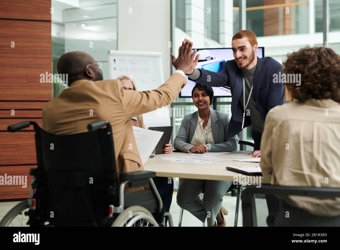 Two happy young intercultural businessmen giving each other high five ...