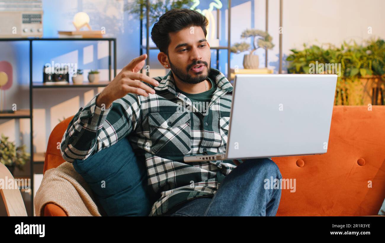 Indian man sitting on couch looking at camera, making video webcam ...